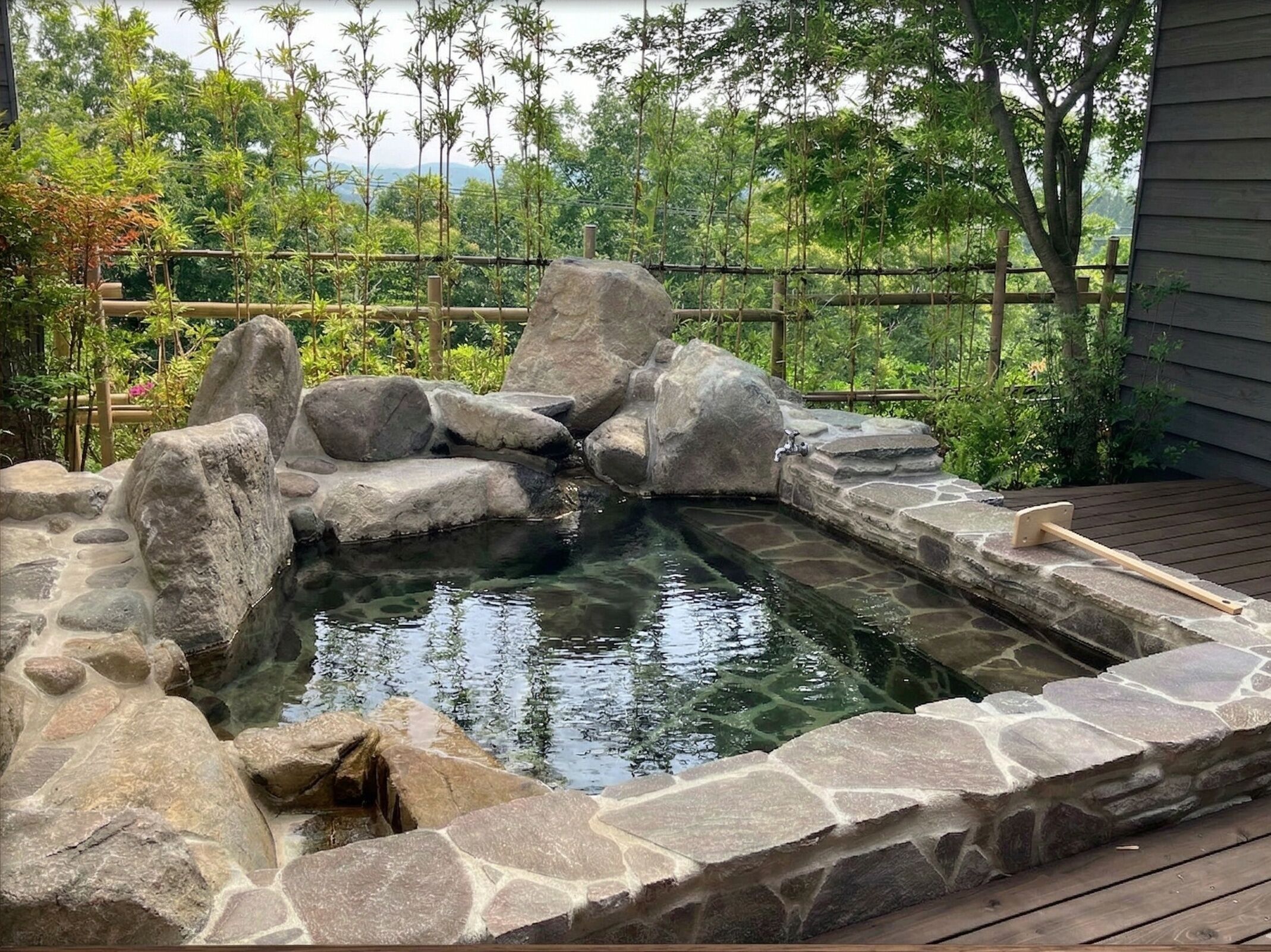 Um lago com margens rochosas, um deck de madeira e paredes de pedra.