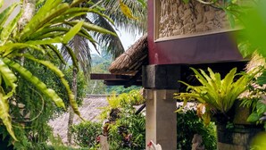 Um jardim tropical com caminho de pedra, estátuas e vegetação exuberante.