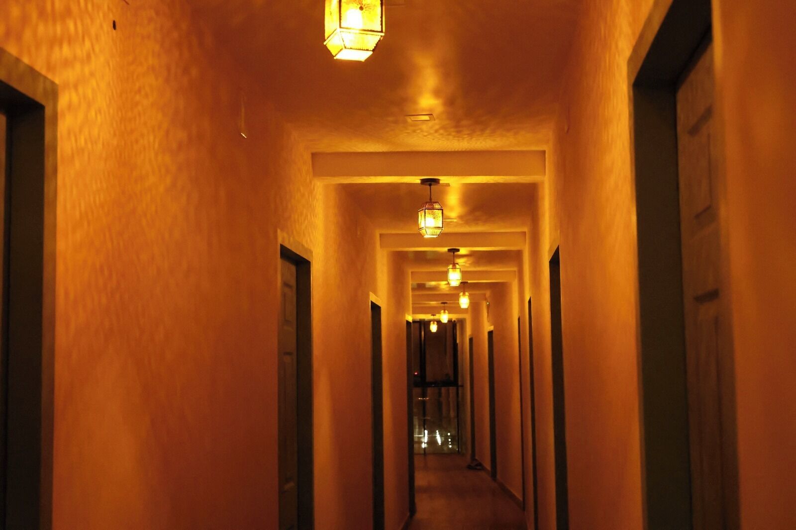 Um corredor com várias portas e luminárias penduradas.
