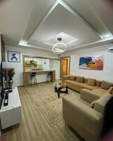 Uma sala de estar moderna com um sofá, mesa de centro e uma área de cozinha com banquetas.