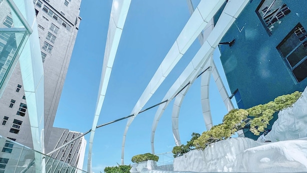 Um edifício moderno com fachada de vidro e uma série de estruturas brancas e curvas.