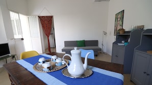 Uma sala de jantar com uma mesa posta para chá, um sofá e um armário.