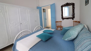 Quarto com cama, duas cadeiras, guarda-roupa e espelho.