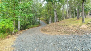Uma trilha de cascalho serpenteia por uma área arborizada, com árvores de ambos os lados.