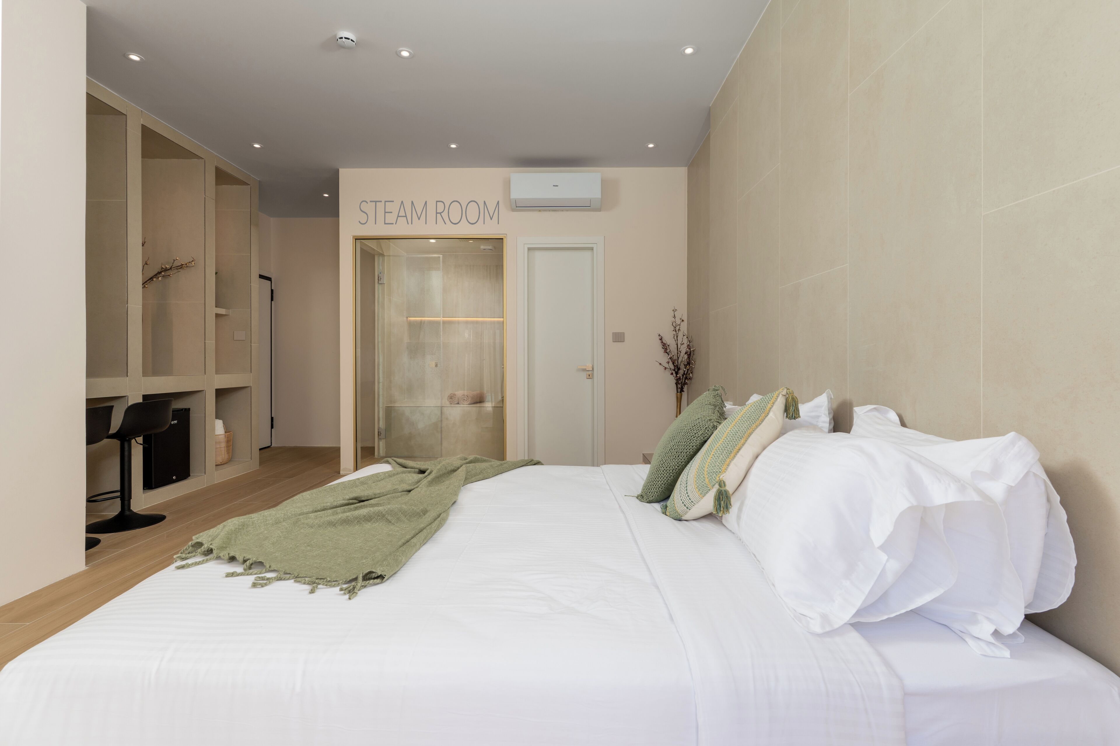 Quarto de hotel moderno com uma cama grande, um cobertor verde e vista para a sala de equipe.