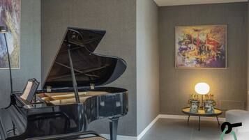 Uma sala de estar moderna com um piano de cauda, uma mesa redonda com abajur e uma grande pintura abstrata na parede.