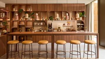 Uma cozinha moderna com armários de madeira, banquetas de bar, luminárias pendentes e diversos eletrodomésticos.