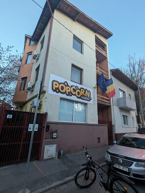 Um edifício com uma placa indicando 'Popcorn Hostel' e a bandeira romena.