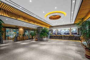 Um lobby espaçoso com balcão de recepção, área de estar e uma parede grande com obras de arte emolduradas.