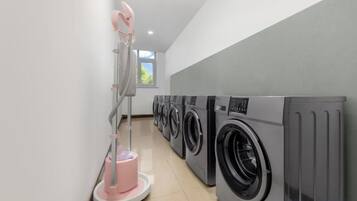 Uma lavanderia com várias máquinas de lavar e um esfregão de piso rosa.