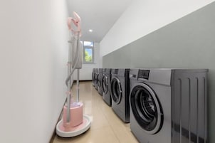 Uma lavanderia com várias máquinas de lavar e um esfregão de piso rosa.