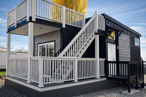Uma casa de dois andares com varanda, escadas e um pequeno terraço.