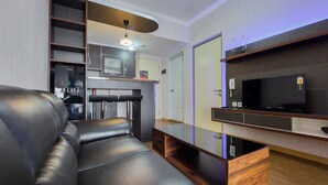 Uma sala de estar moderna com um sofá de couro, uma televisão de tela plana e estantes embutidas.