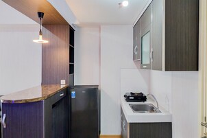 Cozinha compacta com geladeira embutida, pia e bancada.