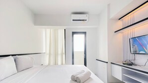 Quarto de hotel com uma cama, uma televisão e um ar condicionado.