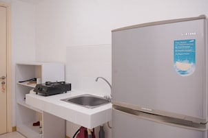 Uma cozinha compacta com bancada branca, pia e geladeira Samsung.