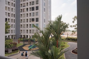 Um edifício residencial com um parquinho e uma palmeira em primeiro plano.