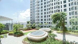Um edifício residencial moderno com várias varandas, um jardim no terraço e um elemento aquático circular.