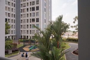 Um edifício residencial com um parquinho e uma palmeira em primeiro plano.