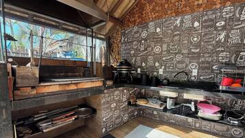 Uma cozinha com forno de tijolos, prateleiras de madeira e parede decorada com ilustrações sobre alimentação.