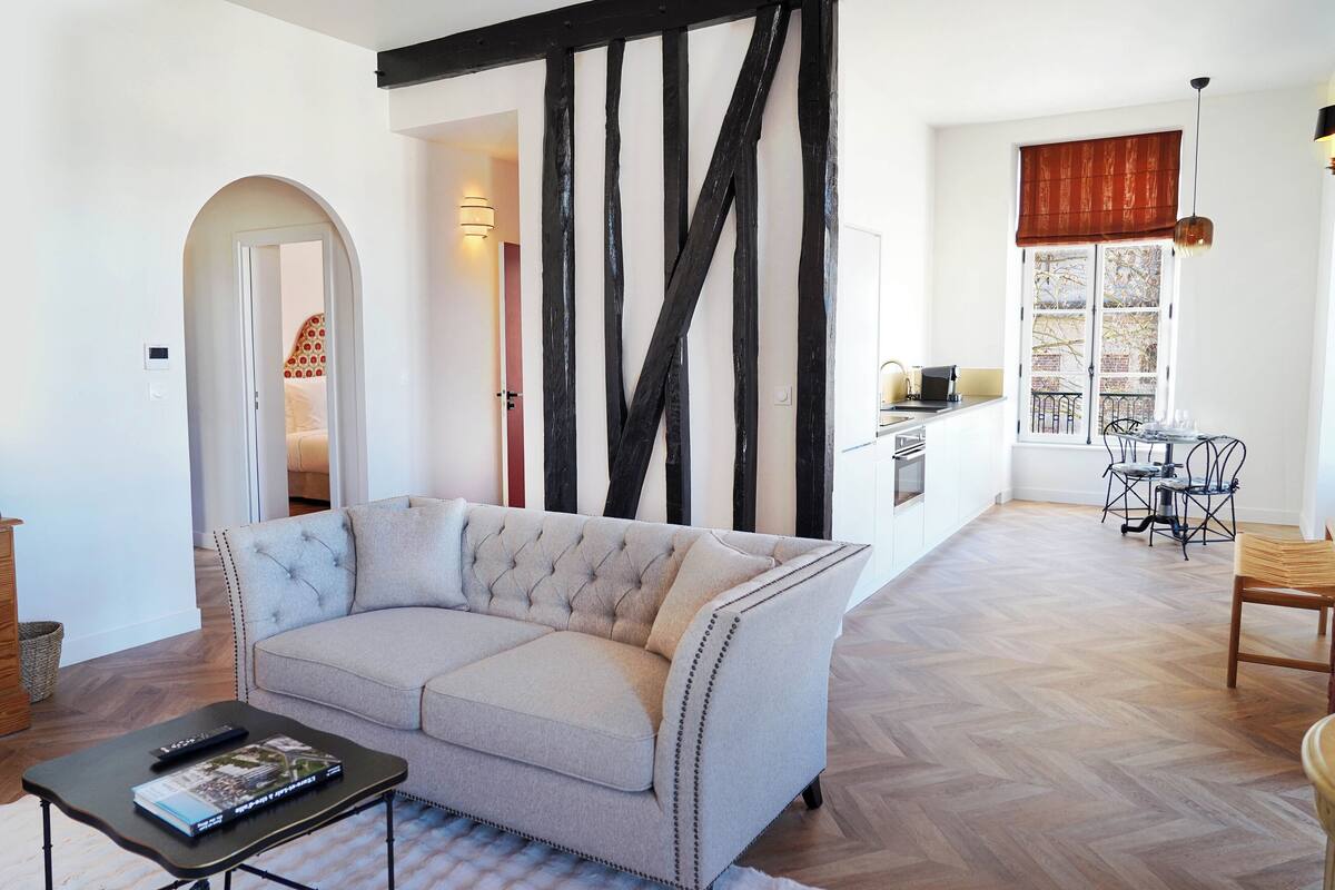 Uma sala de estar com sofá, mesa de centro e área de jantar com mesa e cadeiras.