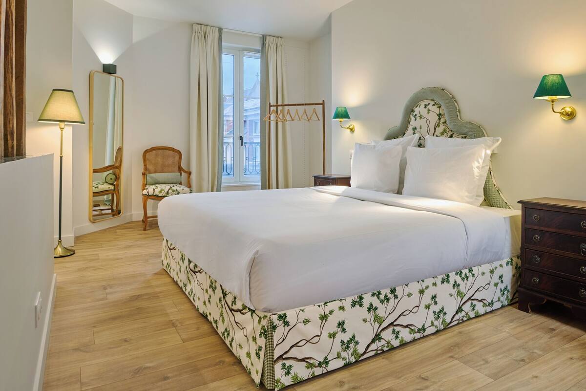 Quarto com uma cama grande, uma cadeira, cômoda e mesa de cabeceira.