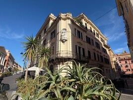 Um edifício histórico com arquitetura clássica, apresentando varandas ornamentadas e um elemento decorativo central.