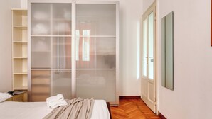 Um quarto com uma cama, um guarda-roupa, uma mesa de cabeceira e um espelho na parede.