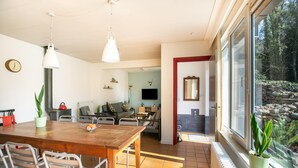 Uma sala de estar moderna com área de jantar, lareira e uma janela grande que oferece vista para o exterior.