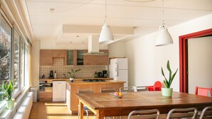 Uma cozinha moderna com armários de madeira, uma ilha central e uma área de refeições com mesa de madeira e cadeiras de metal.
