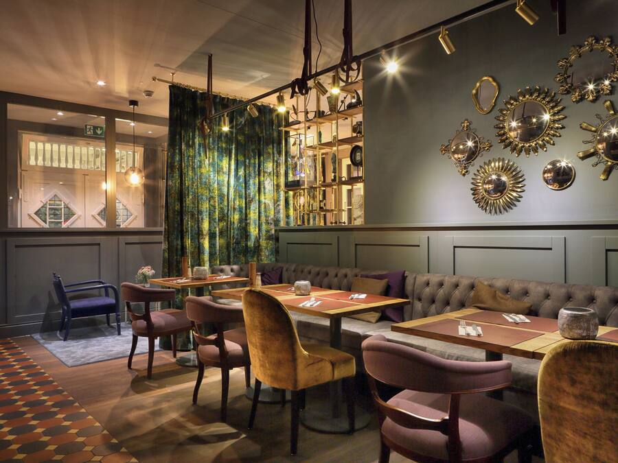 Um restaurante com área de estar acolhedora, bar e exposição de espelhos decorativos.