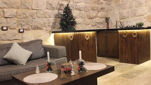 Uma sala de estar aconchegante com uma parede de pedra, uma pequena árvore de Natal e um armário de madeira.