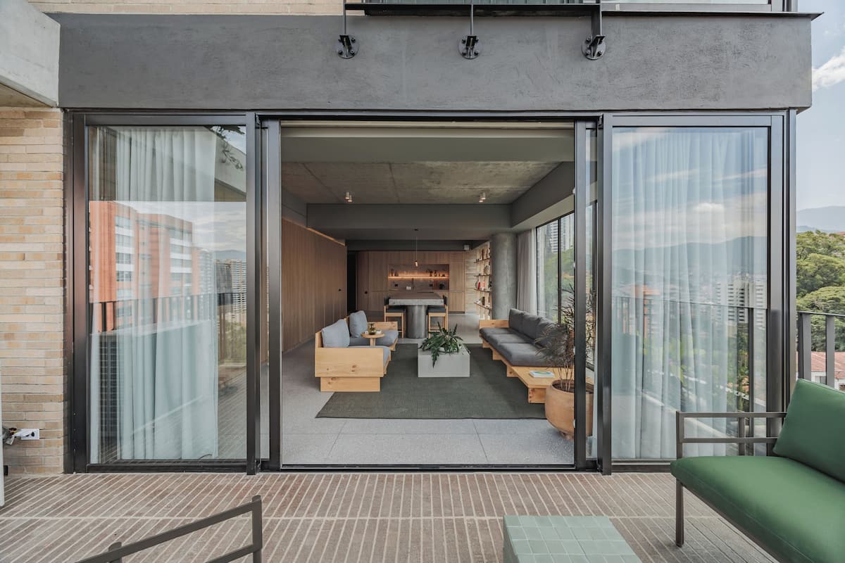 Uma sala de estar moderna com um conjunto de sofá, uma mesa de centro e uma área de jantar visível através de uma porta de vidro.