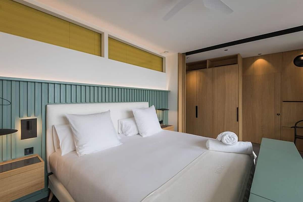 Quarto de hotel moderno com uma cama grande, uma escrivaninha e um guarda-roupa.