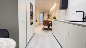 Uma cozinha moderna com ilha central, armários brancos e torneira preta.