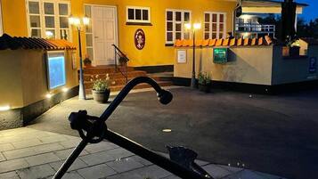 Um edifício com fachada amarela, entrada visível e placa de estacionamento.