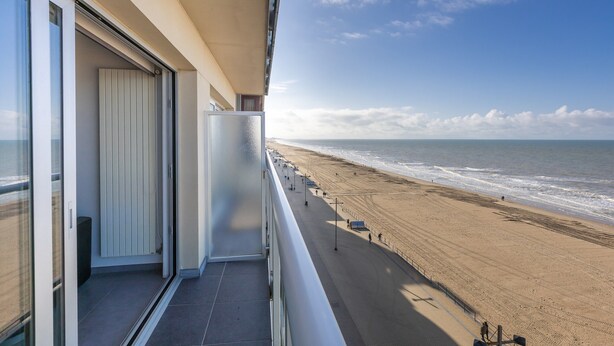 Uma varanda com vista para uma praia arenosa e o oceano.