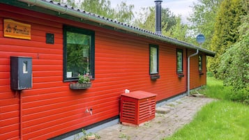 Um edifício vermelho com uma placa indicando 'La Familia', uma janela com uma planta e uma chaminé.