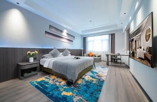 Quarto de hotel moderno com uma cama grande, uma escrivaninha e vista para a cidade.