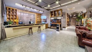 Um lobby de hotel moderno com balcão de recepção, área de bar e assentos.