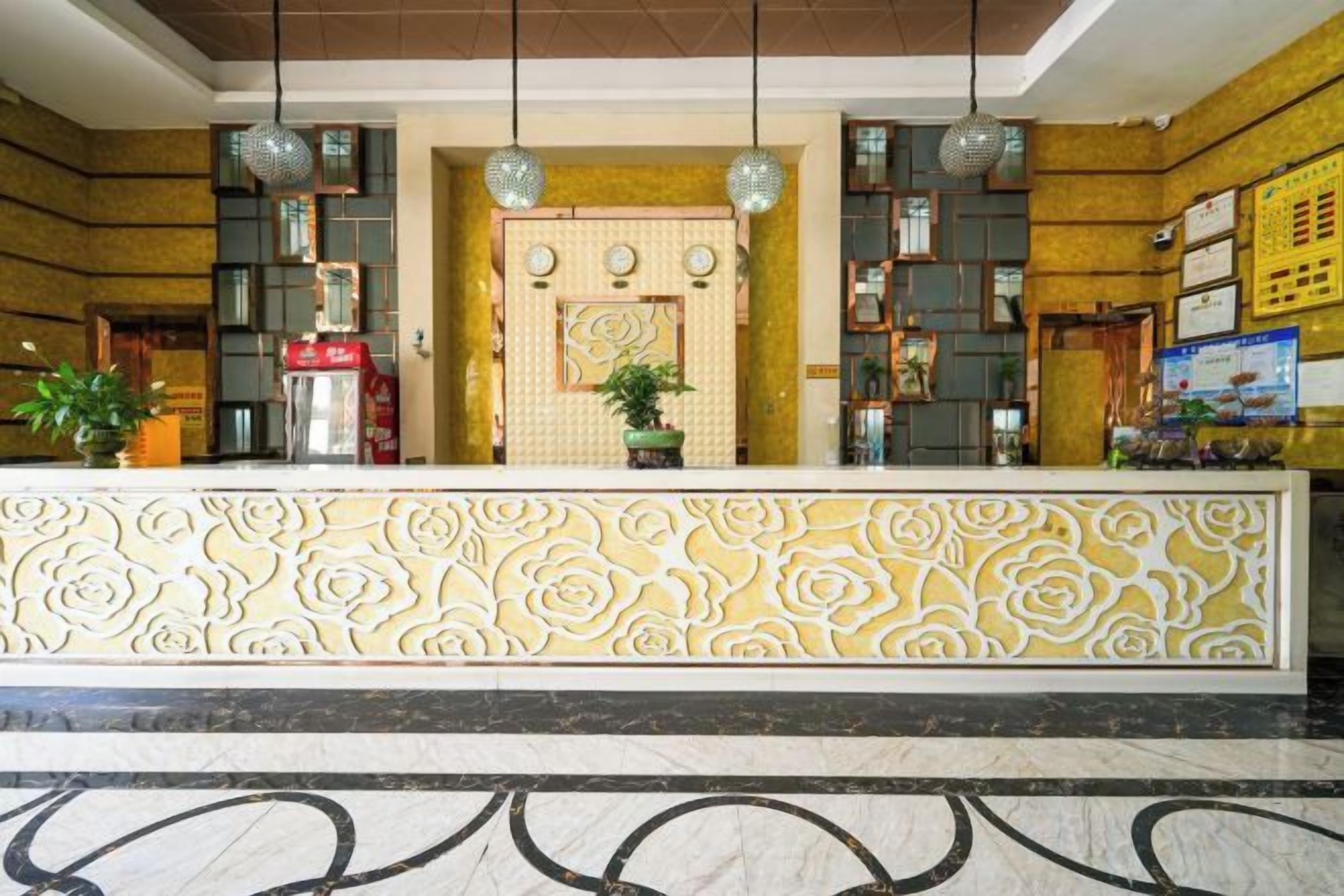 Uma área de recepção com balcão de mármore, luminárias pendentes e um painel decorativo.