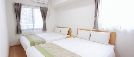 Quarto de hotel com duas camas, piso de madeira e ar condicionado.