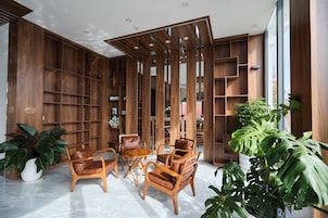 Um interior moderno com estantes de madeira, poltronas de couro e plantas em vasos.