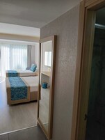 Quarto de hotel com duas camas, um espelho grande e vista para o quarto vizinho.