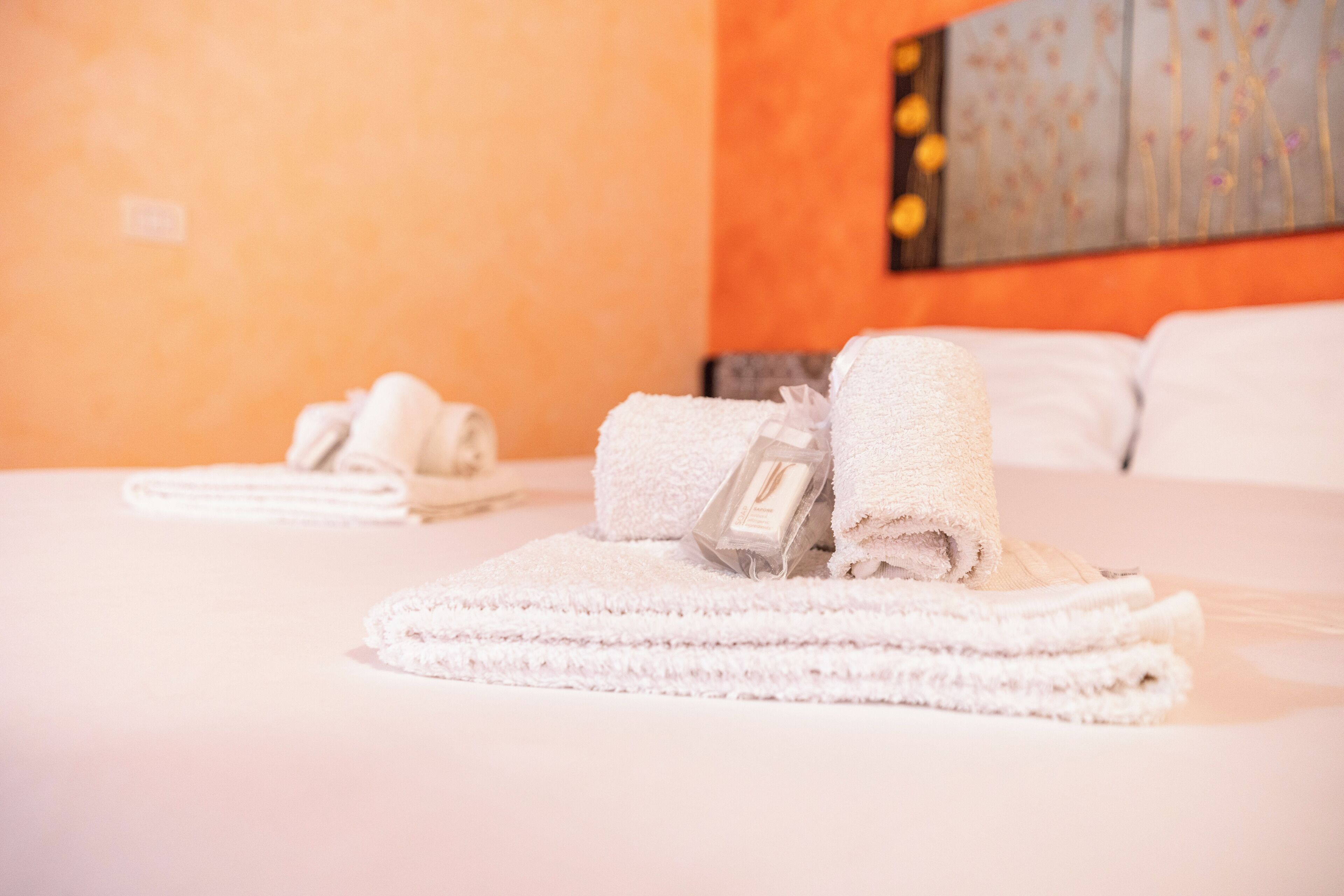 Uma cama bem arrumada com toalhas dobradas e um pequeno frasco de loção.