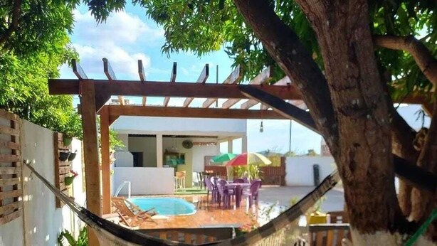 Uma rede em um quintal com piscina, móveis de pátio e uma pérgula.