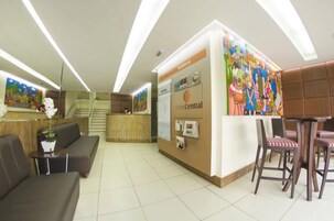 Uma área de recepção de hotel com balcão, espaço de estar e escadaria.