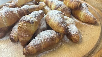 Uma tábua de madeira com diversos doces polvilhados com açúcar de confeiteiro.
