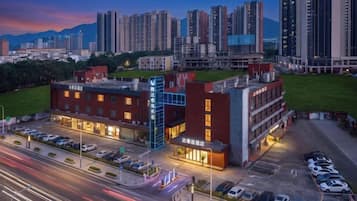 Um hotel com vários andares, com estacionamento em frente, rodeado por edifícios altos.