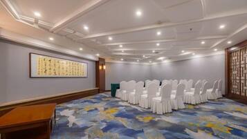 Uma sala de conferências com carpete estampado, cadeiras brancas e uma grande obra de arte emoldurada na parede.